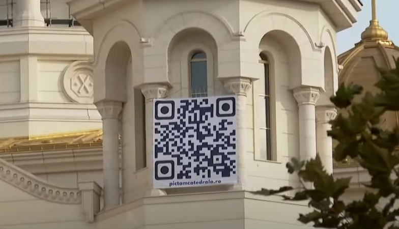 Turlă a Catedralei Mântuirii Neamului cu banner cu un cod QR. Care este ...
